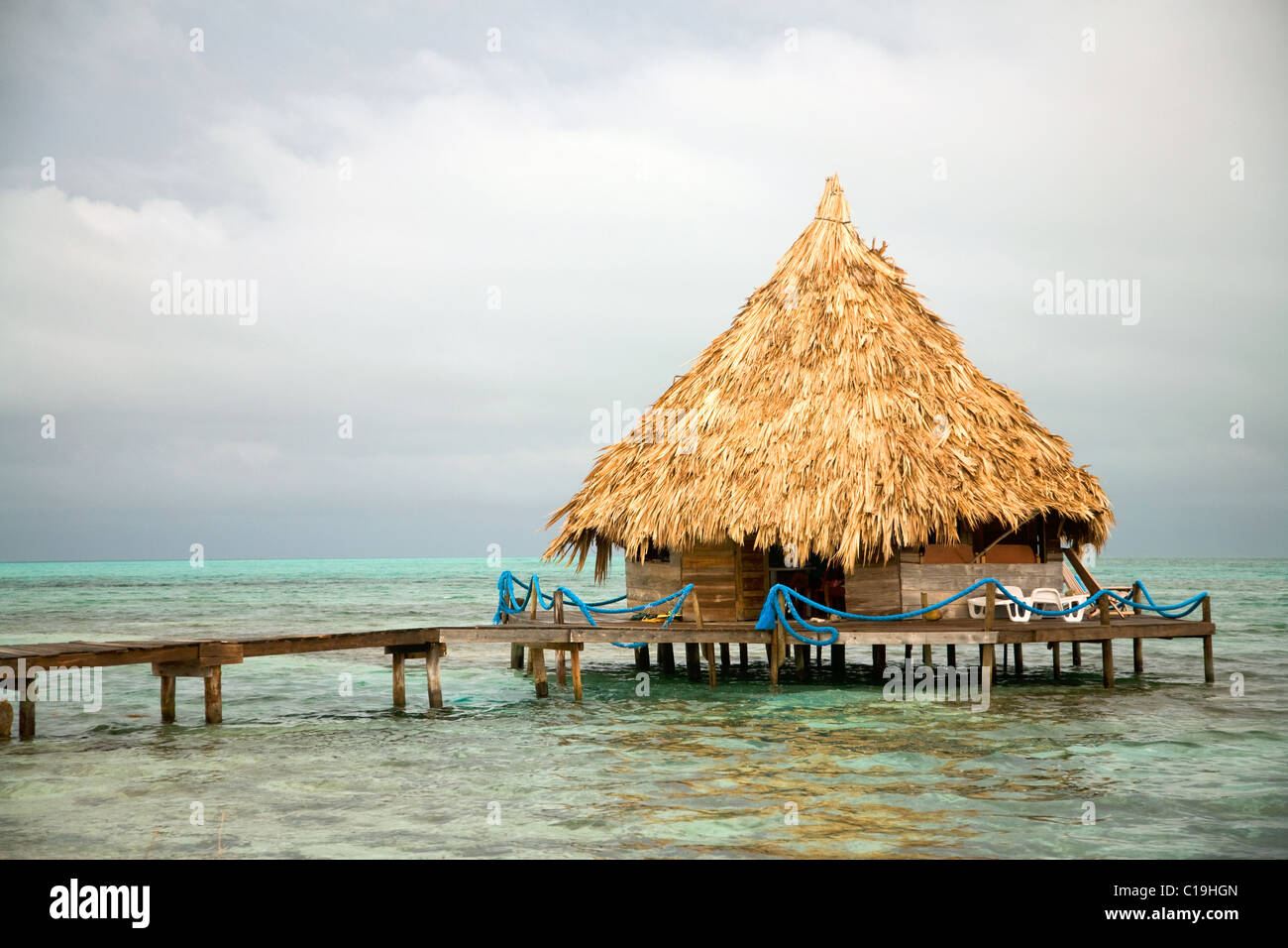 Palm roofed wooden hut over a shallow reef lagoon in Glovers Atoll ...