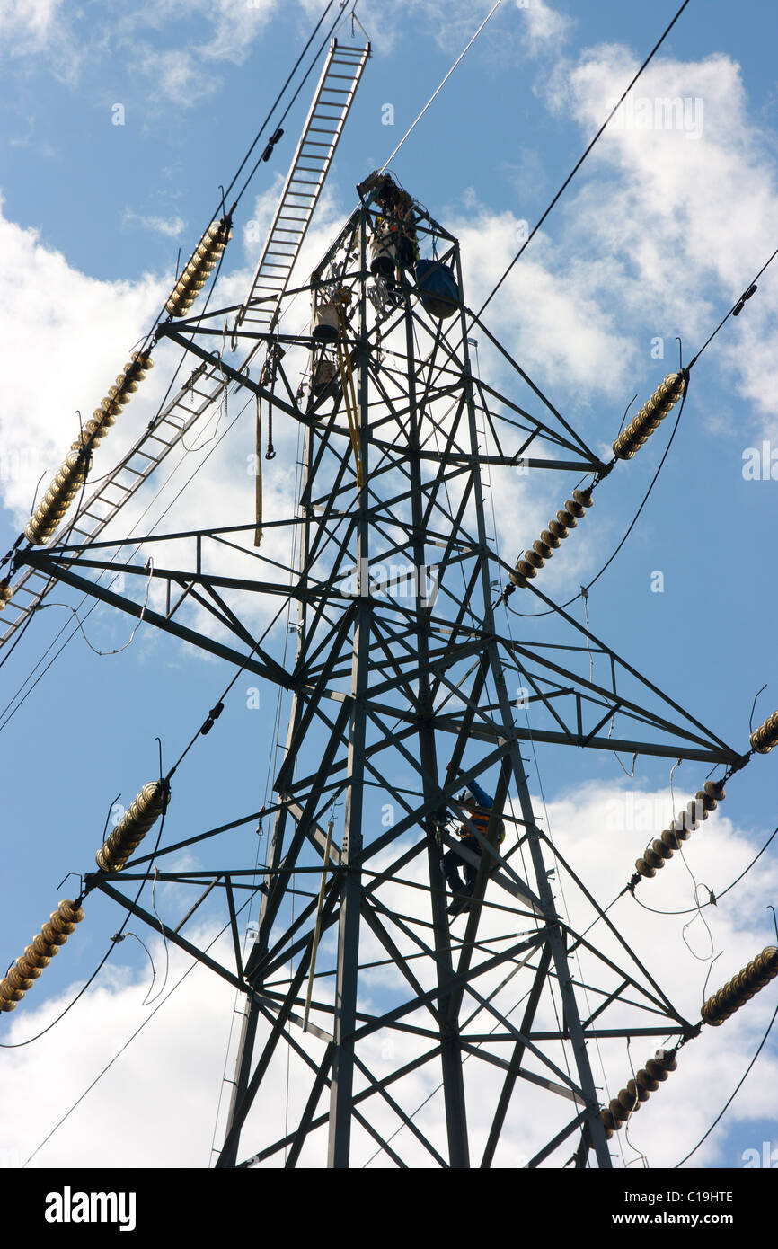 Engineer climbing on electricity pylon Stock Photo - Alamy