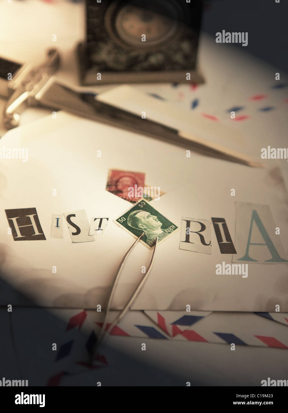 historic Hitler postage stamp on opened white envelope; tweezers and ...