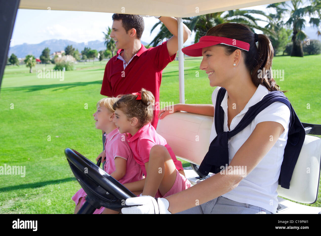 golf course family father mother and daughters in buggy green grass ...