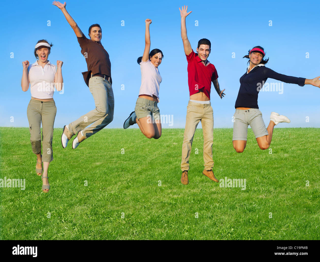 Jumping young people happy group in meadow blue sky outdoor Stock Photo ...