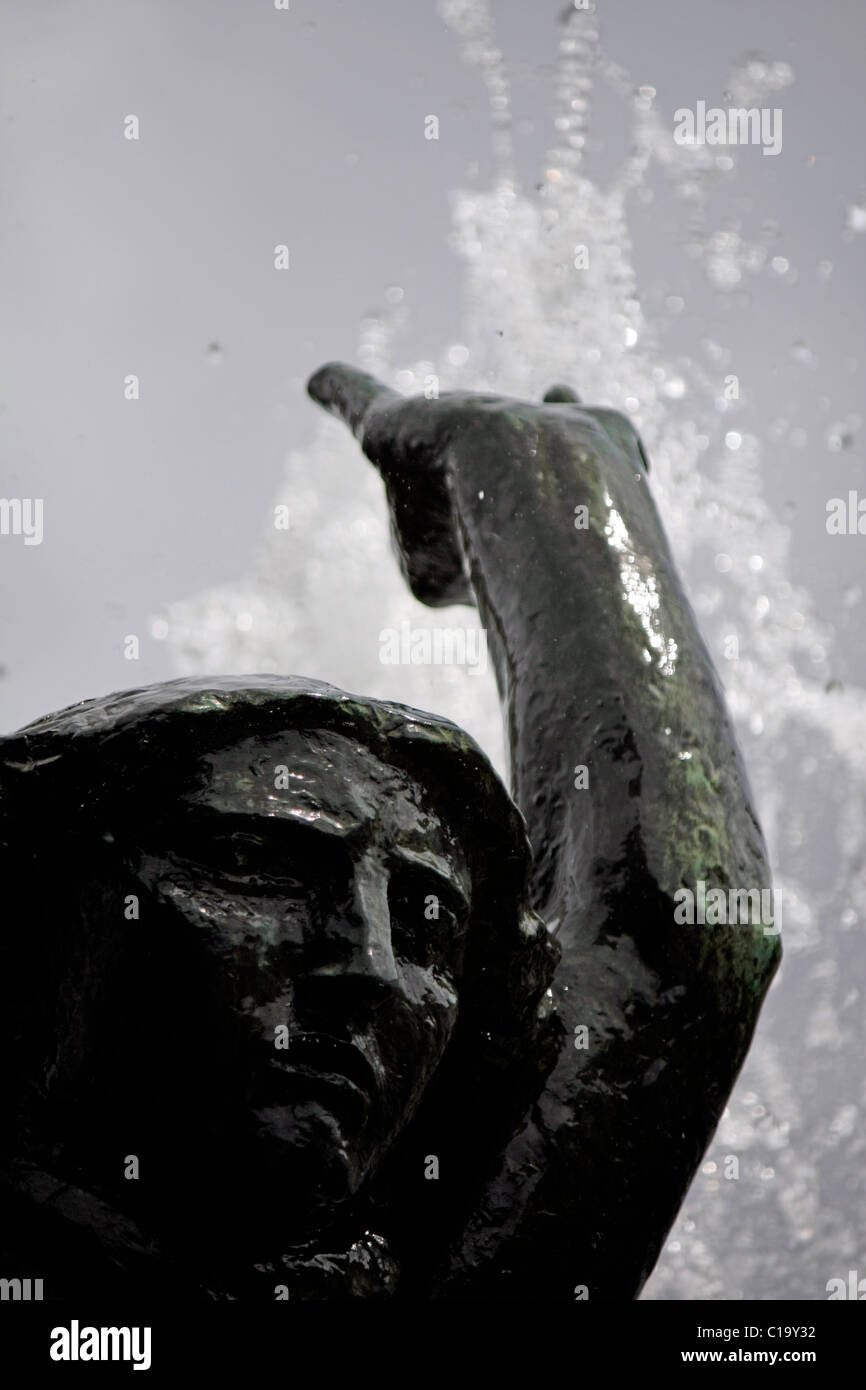 Closeup view of the female face of a iron statue with bursts of water ...