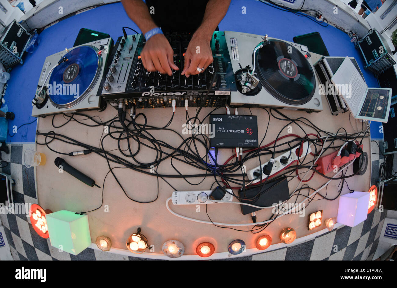 DJ performing live, mixing music using mixer and scratch vinyl record ...