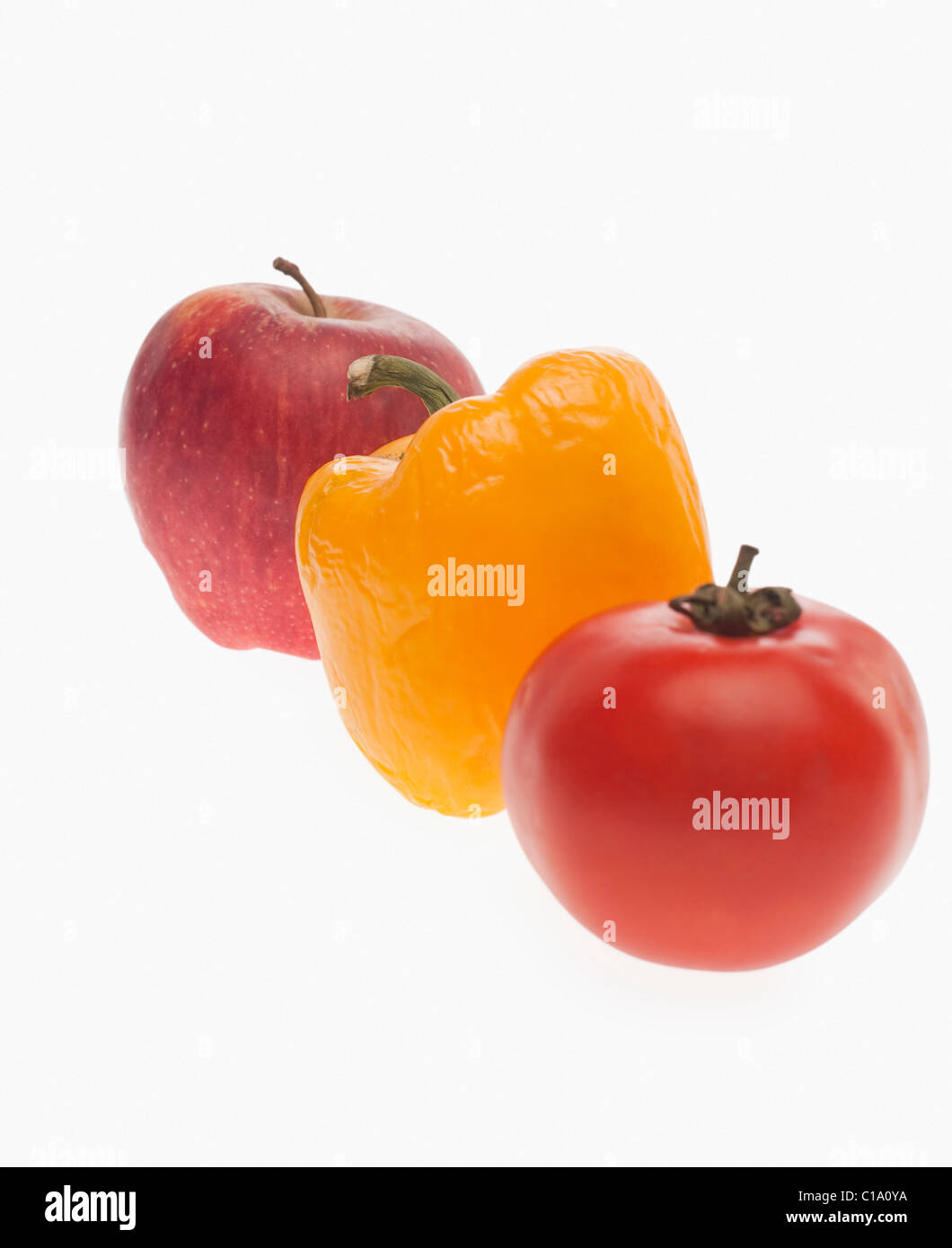 Close-up of an apple and a tomato with a yellow bell pepper Stock Photo ...