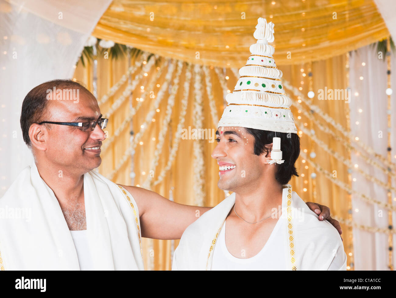 Bridegroom smiling with priest in wedding mandap during Bengali wedding ...