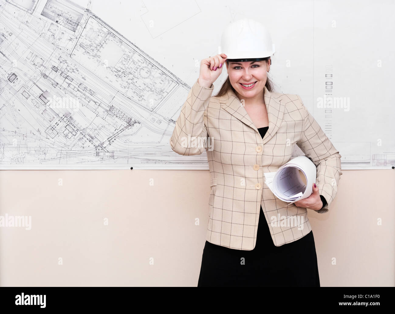 One young woman a architect standing near the big blueprint on wall and ...