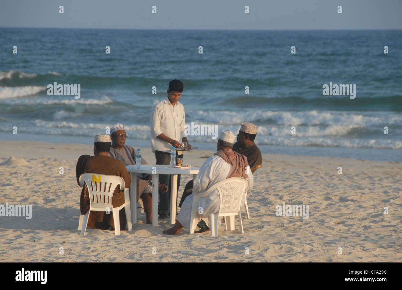 Waiter serves Omanis drinks on the beach at Salalah, Southern Oman ...