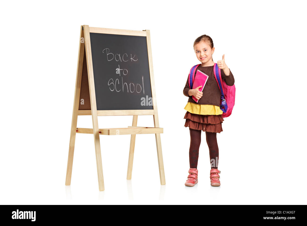 A child next to a school board holding book and showing thumb up Stock ...