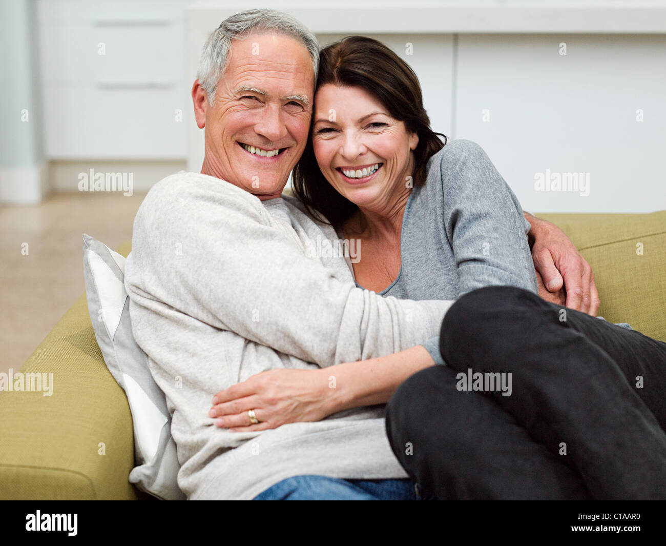 Mature couple embracing on sofa Stock Photo - Alamy