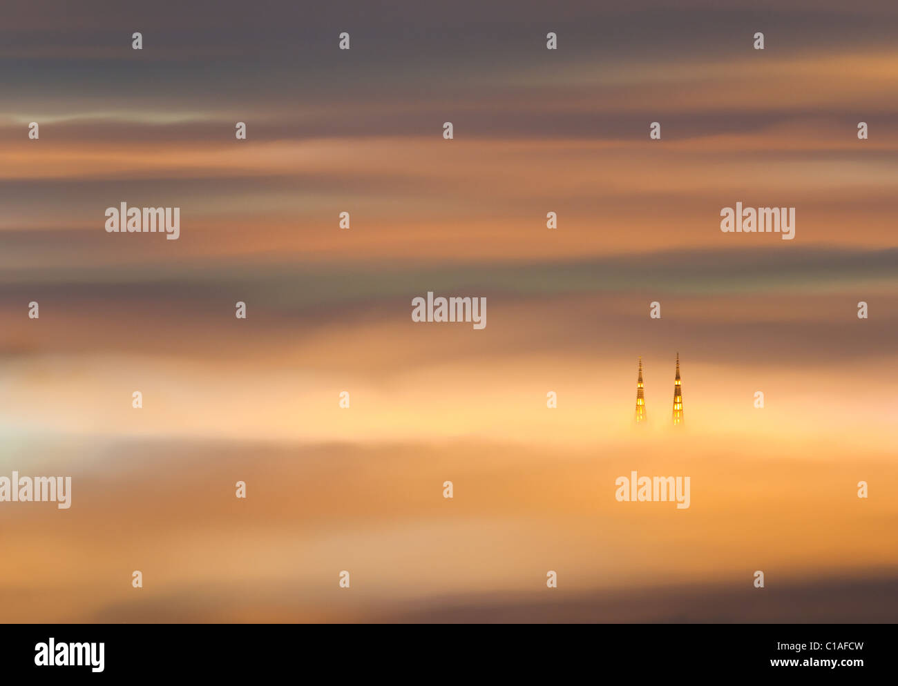 Cathedral towers peaking out of the fog. City lights shining below the ...