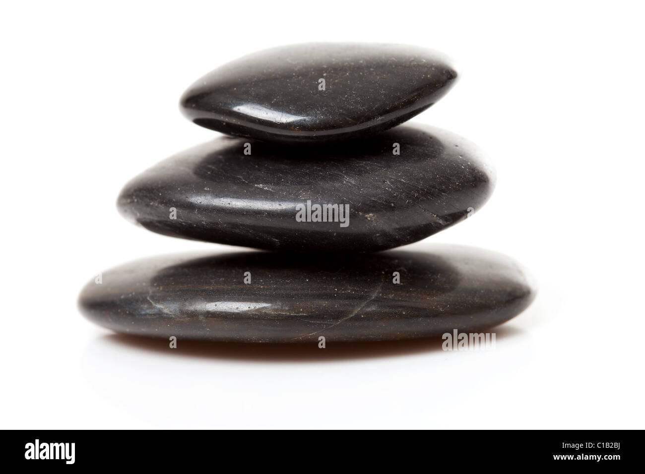 pile of three black pebbles over white background Stock Photo - Alamy