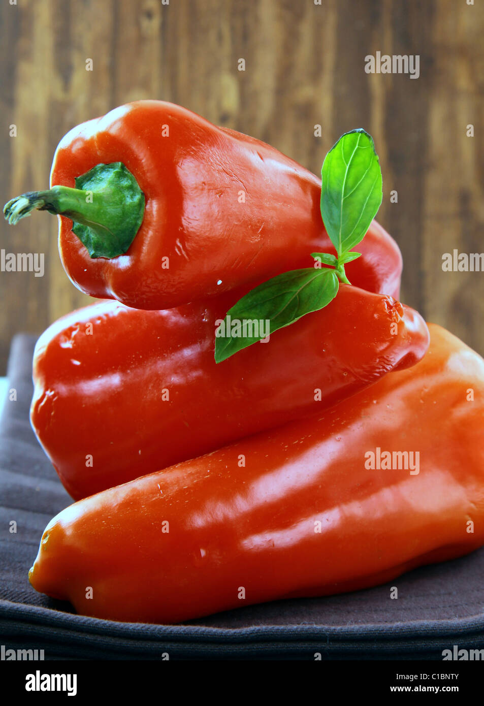 three red pepper on each other on a brown background Stock Photo - Alamy