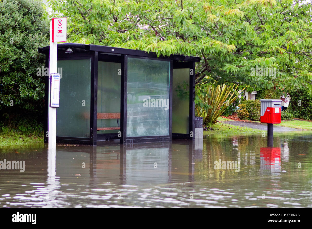 A bus stop and post box are flooded as heavy rainfall causes local ...