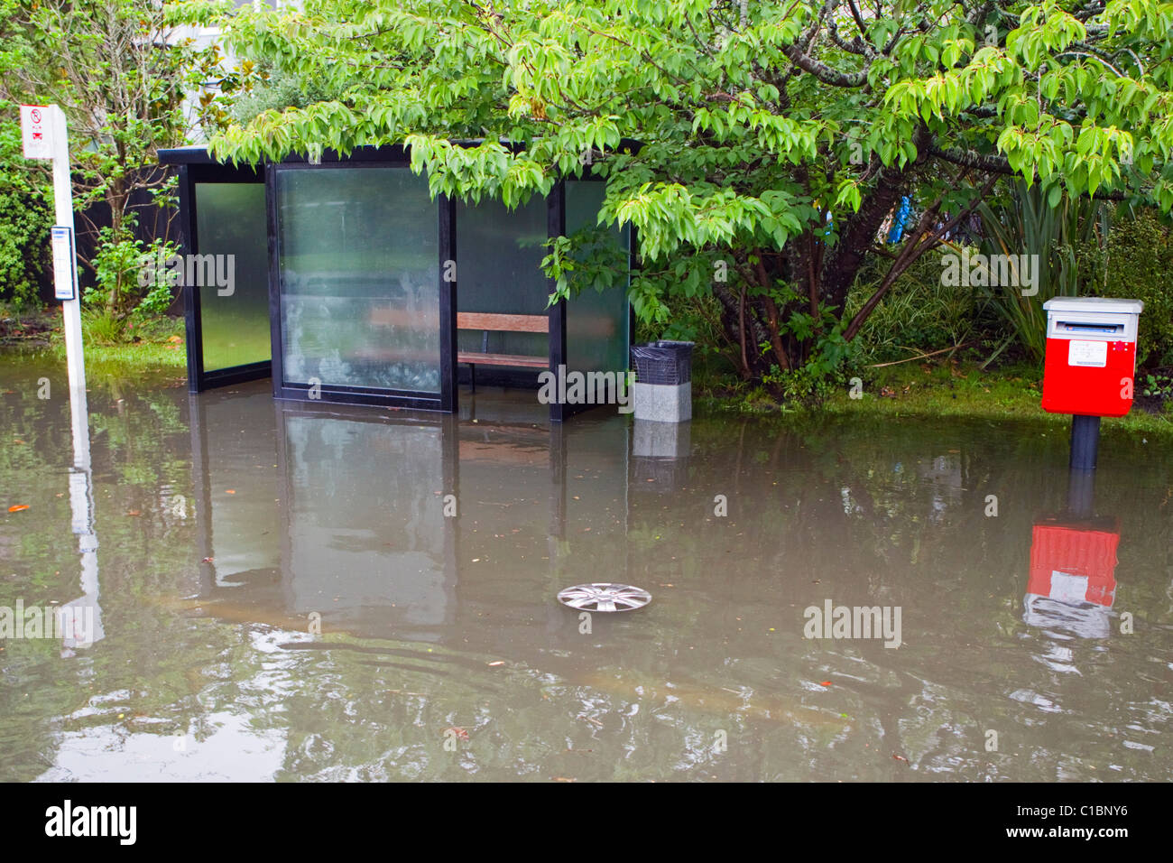 A bus stop and post box are flooded as heavy rainfall causes local ...