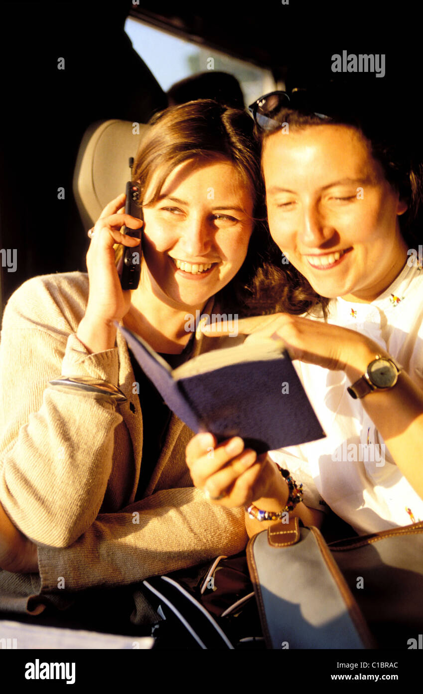 France, two young ladies on the phone, reading a book at the same time ...