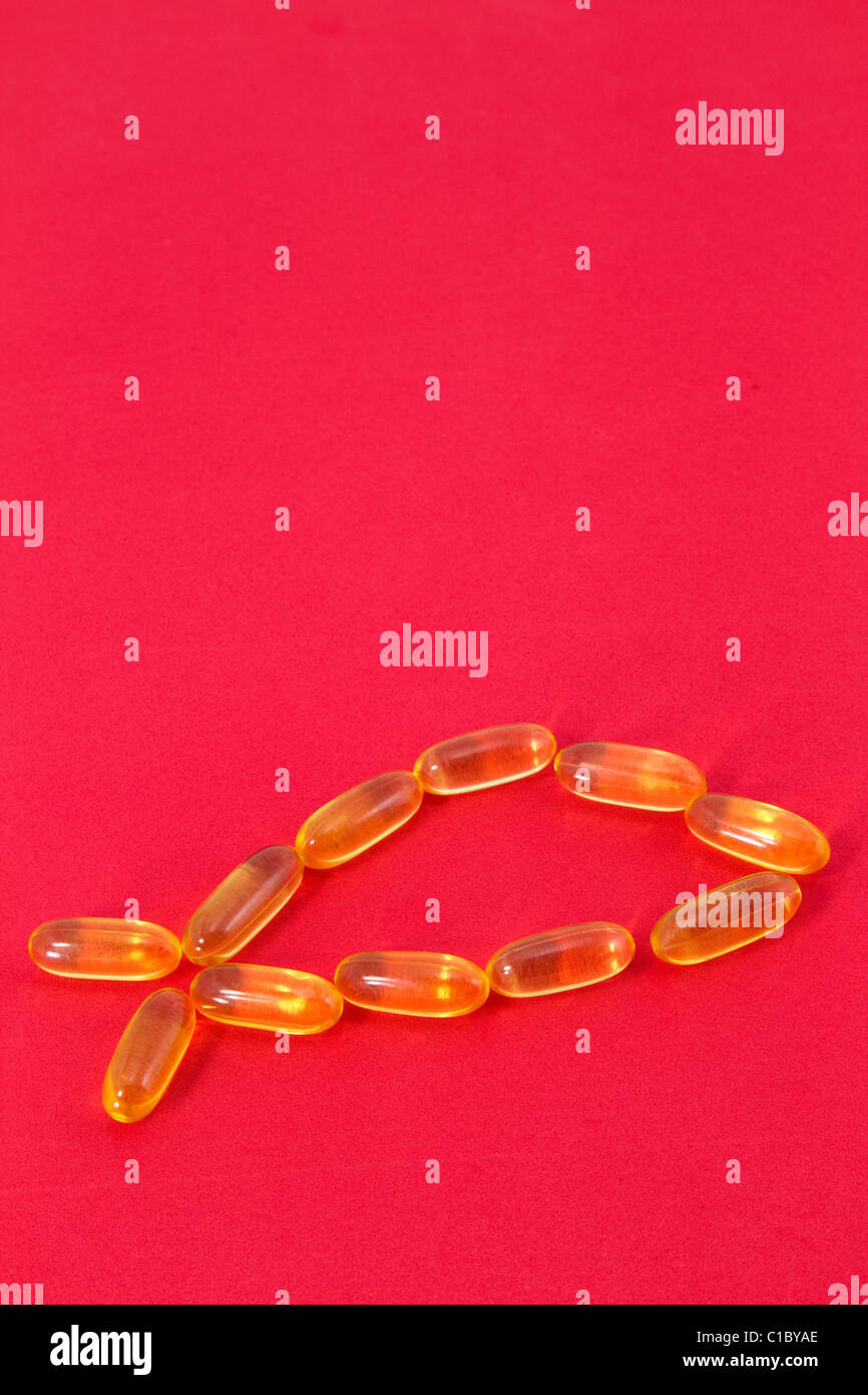 Richly golden fish oil capsules placed in the symbolic shape of a fish ...