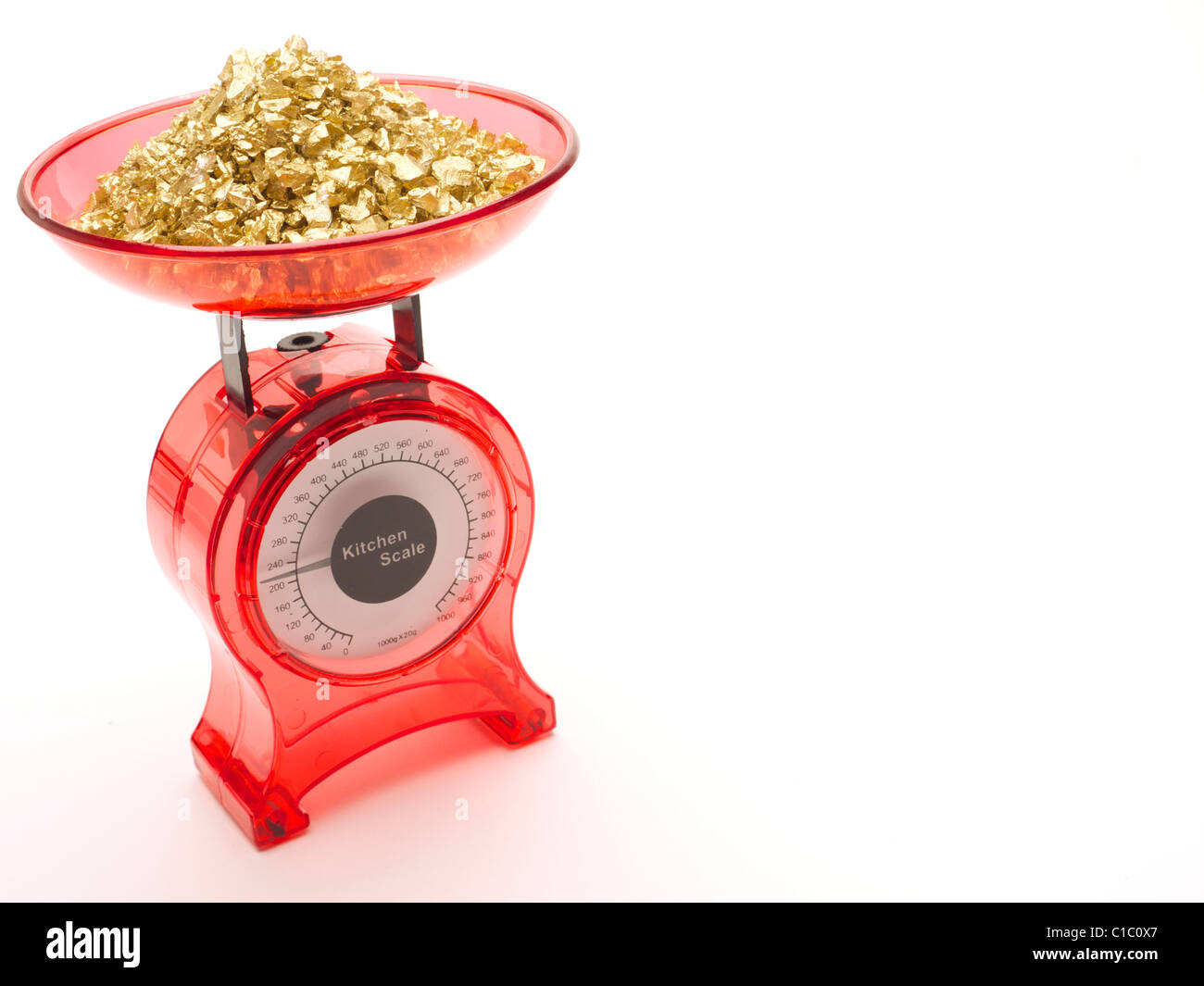 Red kitchen scales with a pile of gold being weighed Stock Photo - Alamy