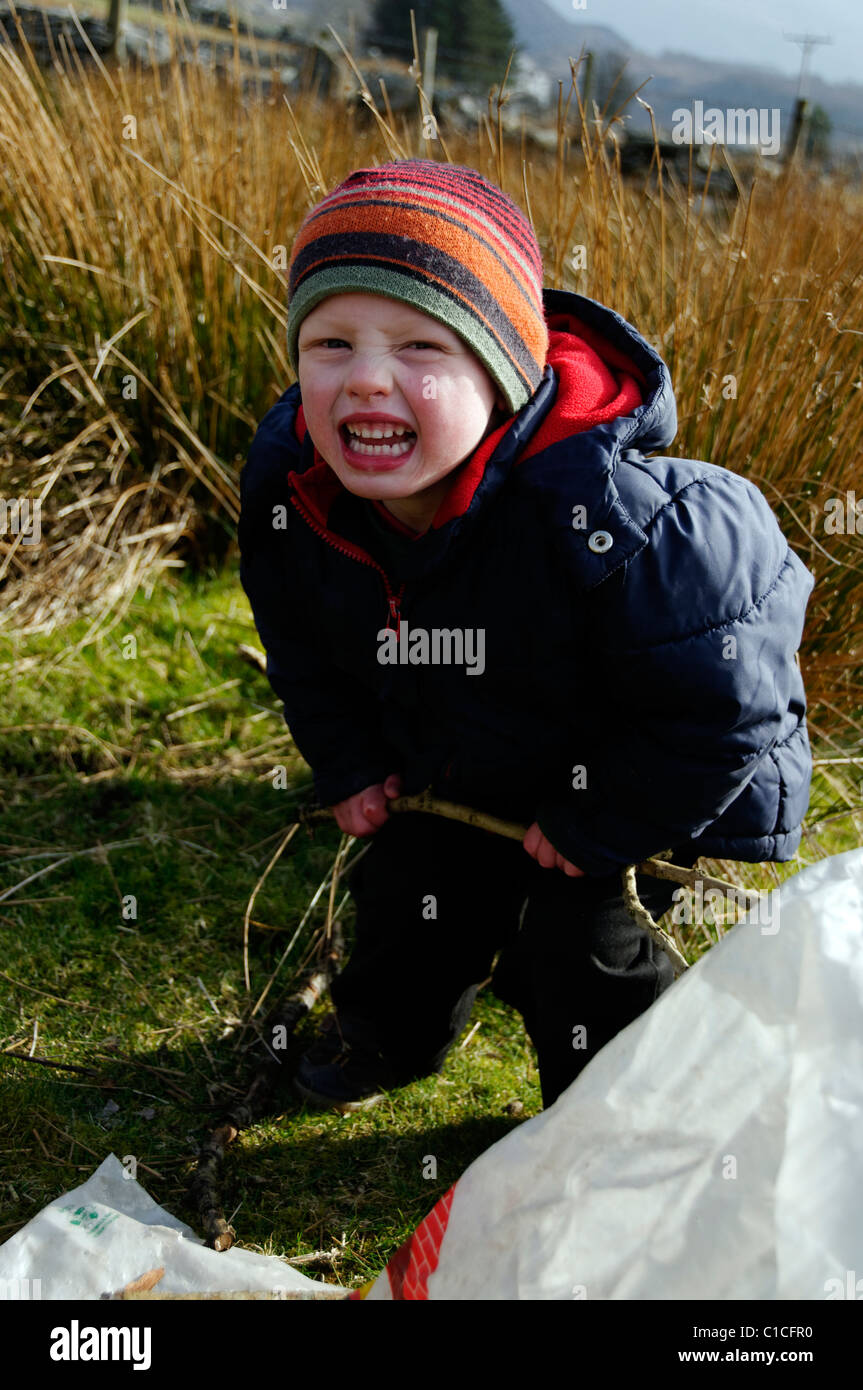 A young boy breaking up and collecting kindling Stock Photo - Alamy