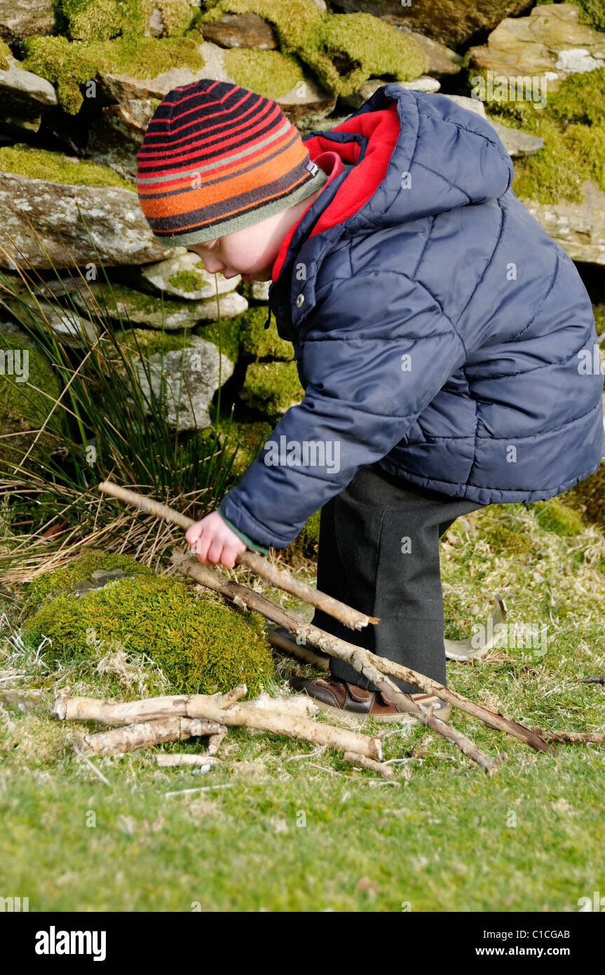 A young boy breaking up and collecting kindling Stock Photo - Alamy