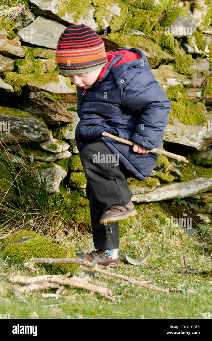 A young boy breaking up and collecting kindling Stock Photo - Alamy