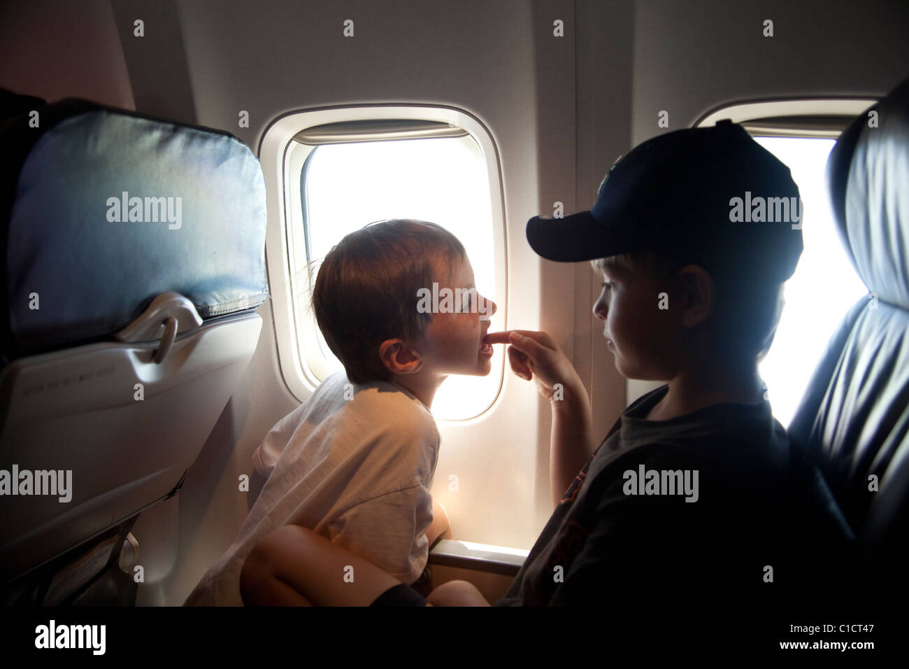 Two brothers playing on a plane during a long flight to visit their ...