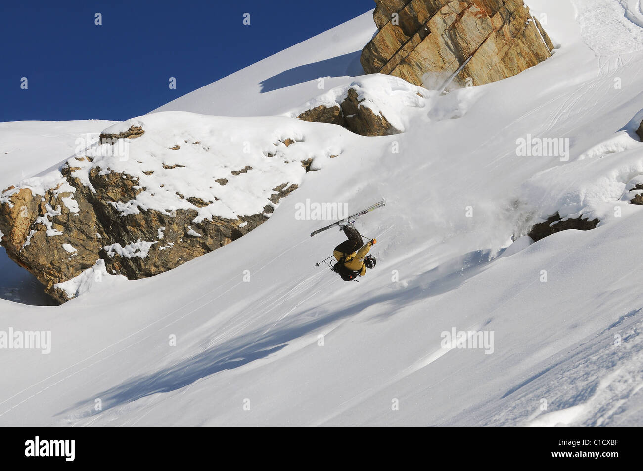A skier performs a front flip off a rock off piste in the ski resort of ...
