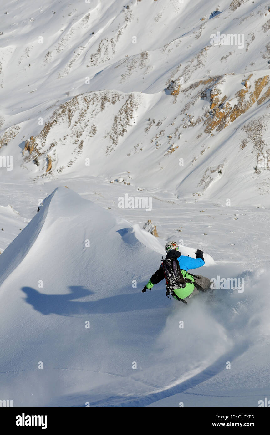 A snowboarder carves a turn in deep powder snow off piste in the Les ...