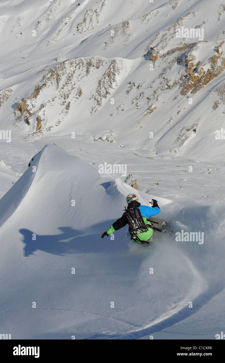 A snowboarder carves a turn in deep powder snow off piste in the Les ...