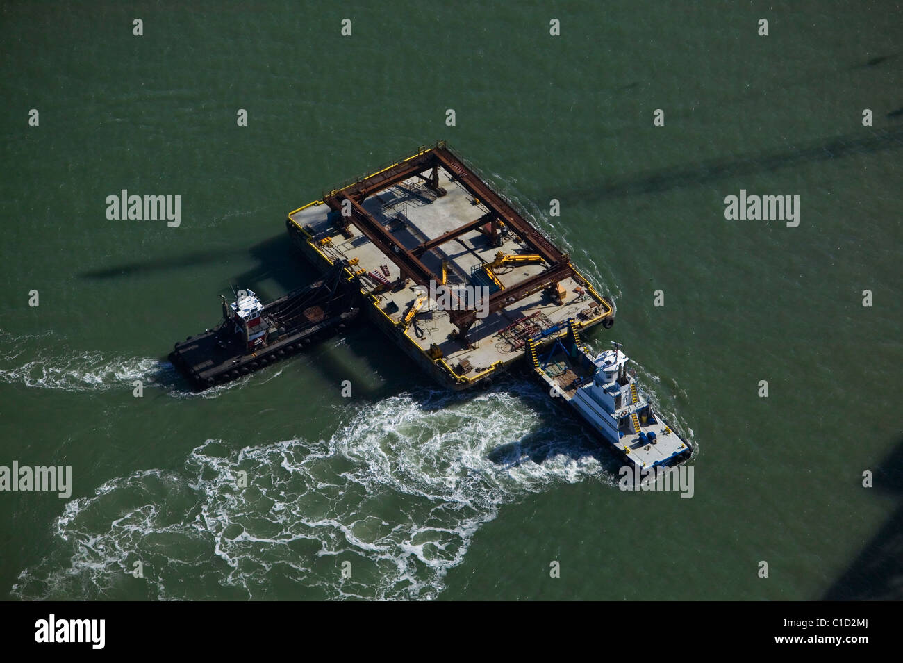 aerial view above tugboats holding construction barge in position San ...