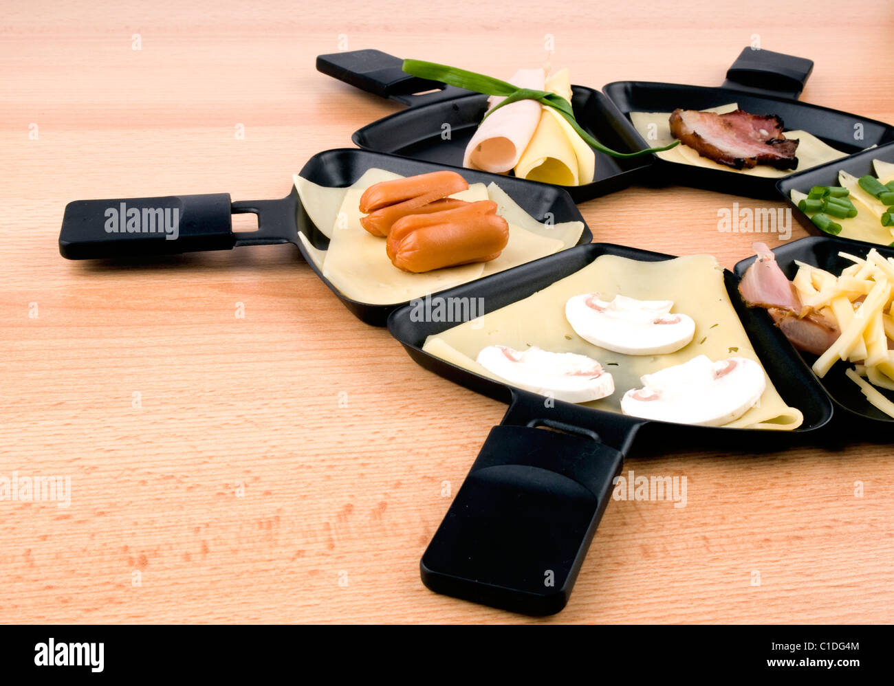 Raclette pans with edam cheese and ham, bacon, mushroom, spring onion ...
