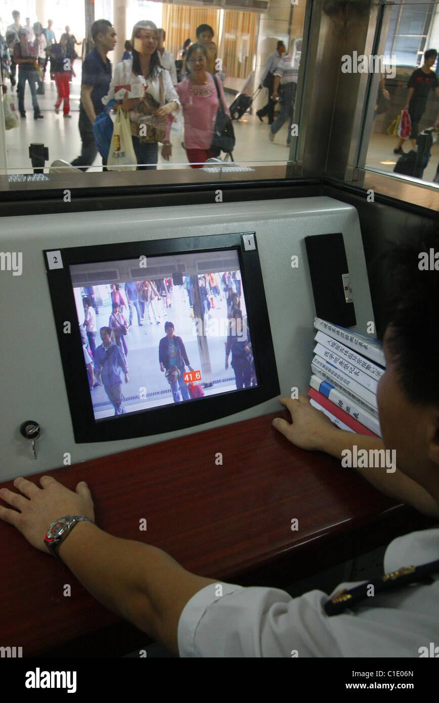 A Chinese quarantine officer checks the body temperature of passengers ...