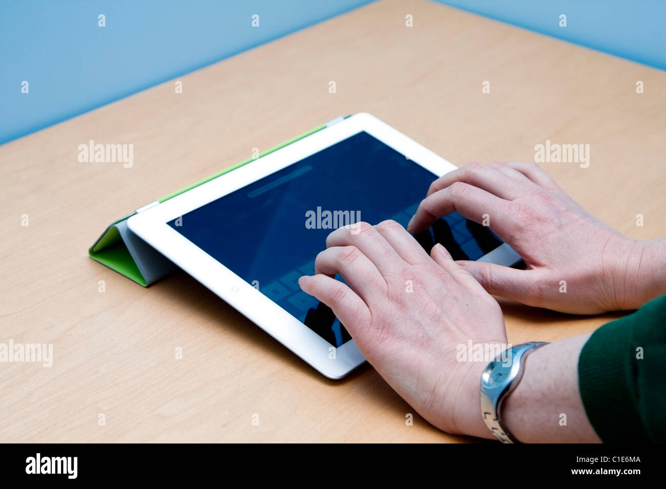 Female user hands typing on the new iPad 2 from Mac Apple, on a wooden ...