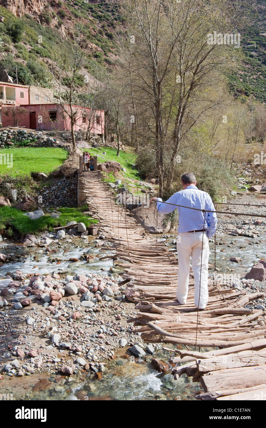 A tourist crossing a rickety bridge in the Ourika Valley near Marrakech ...