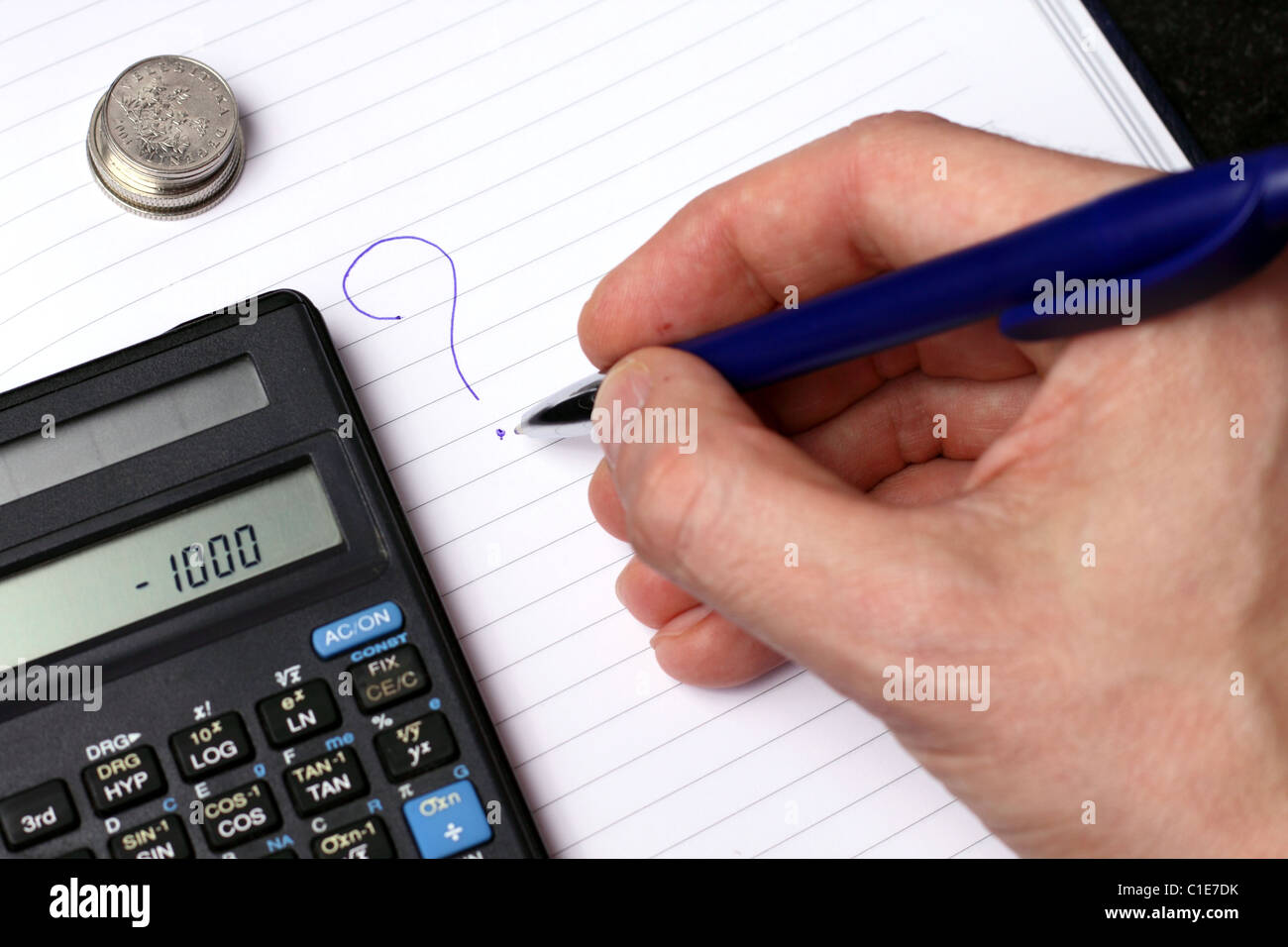 Coins, calculator, hand writing on white striped paper with blue pen ...