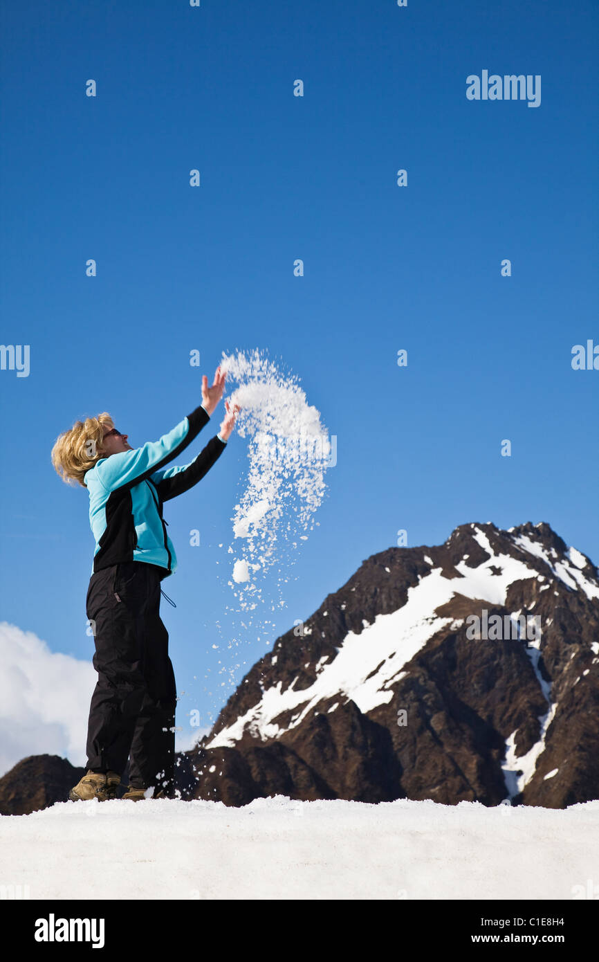 Woman throwing snow in air on top of snowdrift in spring in the Copper ...