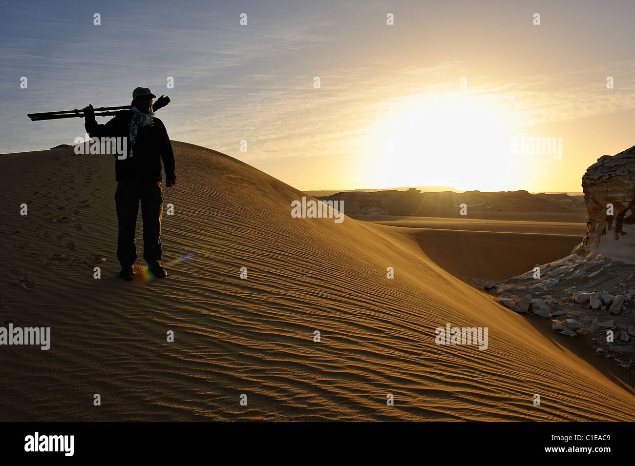 Man photographer holding a tripod with a camera on his shoulder and ...