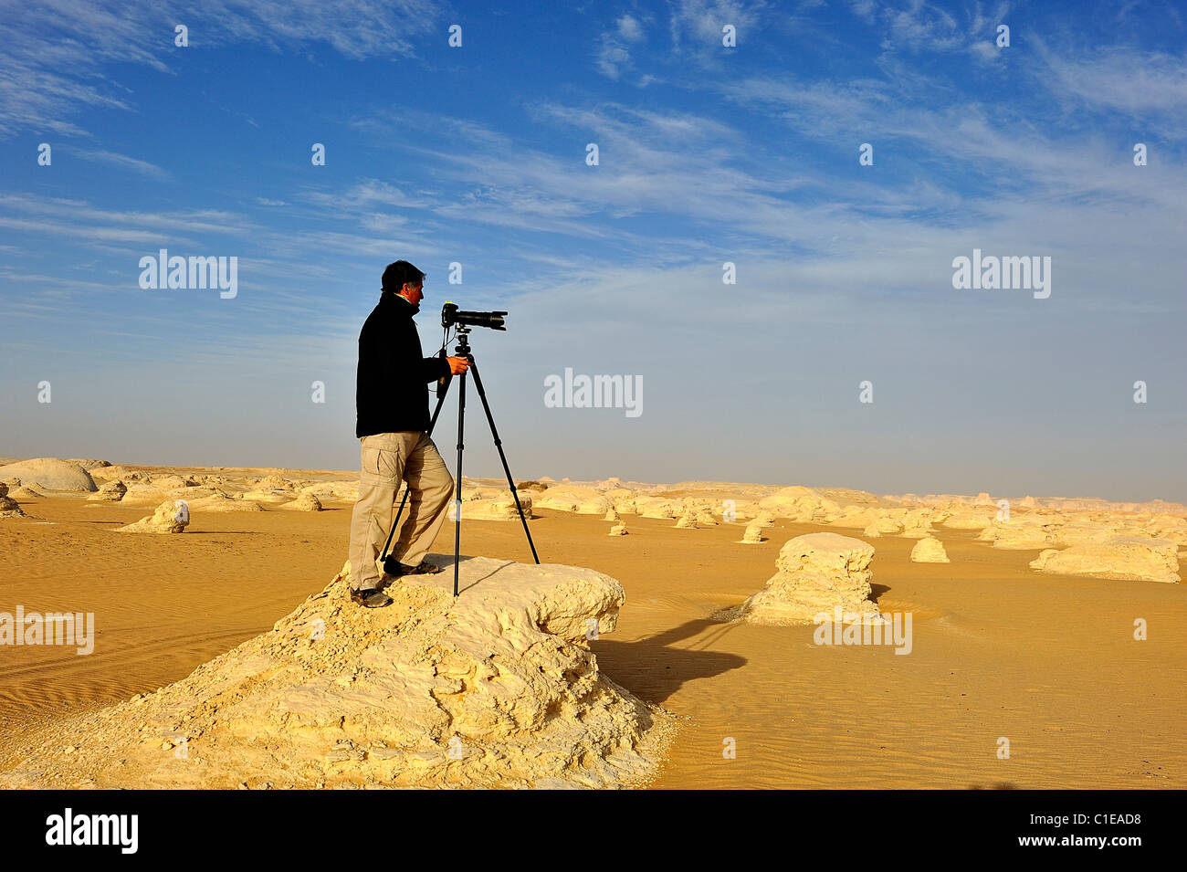 Man photographer shooting sand dunes with a camera on a tripod in the ...