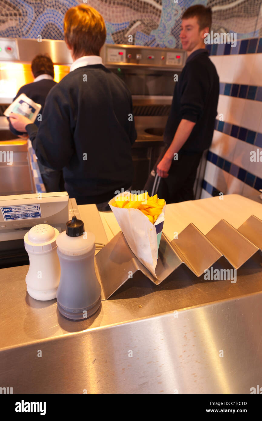 Inside a British fish and chip shop with focus on the bag of chips in ...