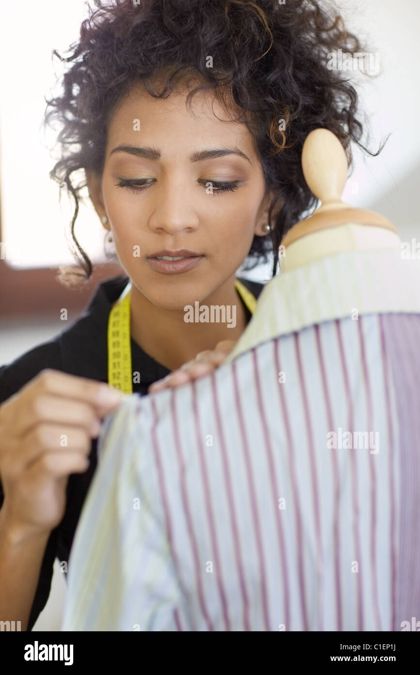 Young hispanic female dressmaker adjusting clothes on tailoring ...