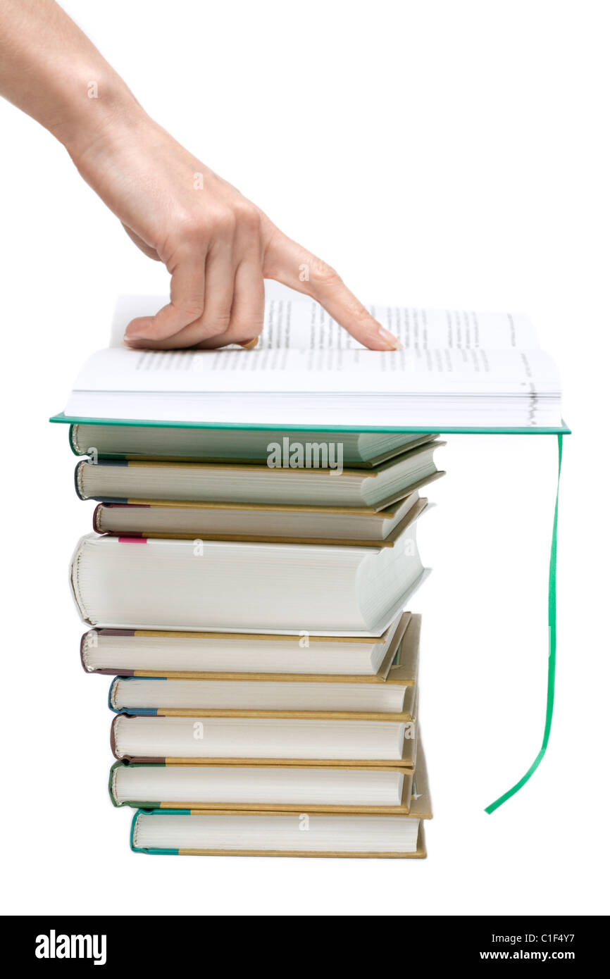 Openning book on pile of the books, hand points to text Stock Photo - Alamy