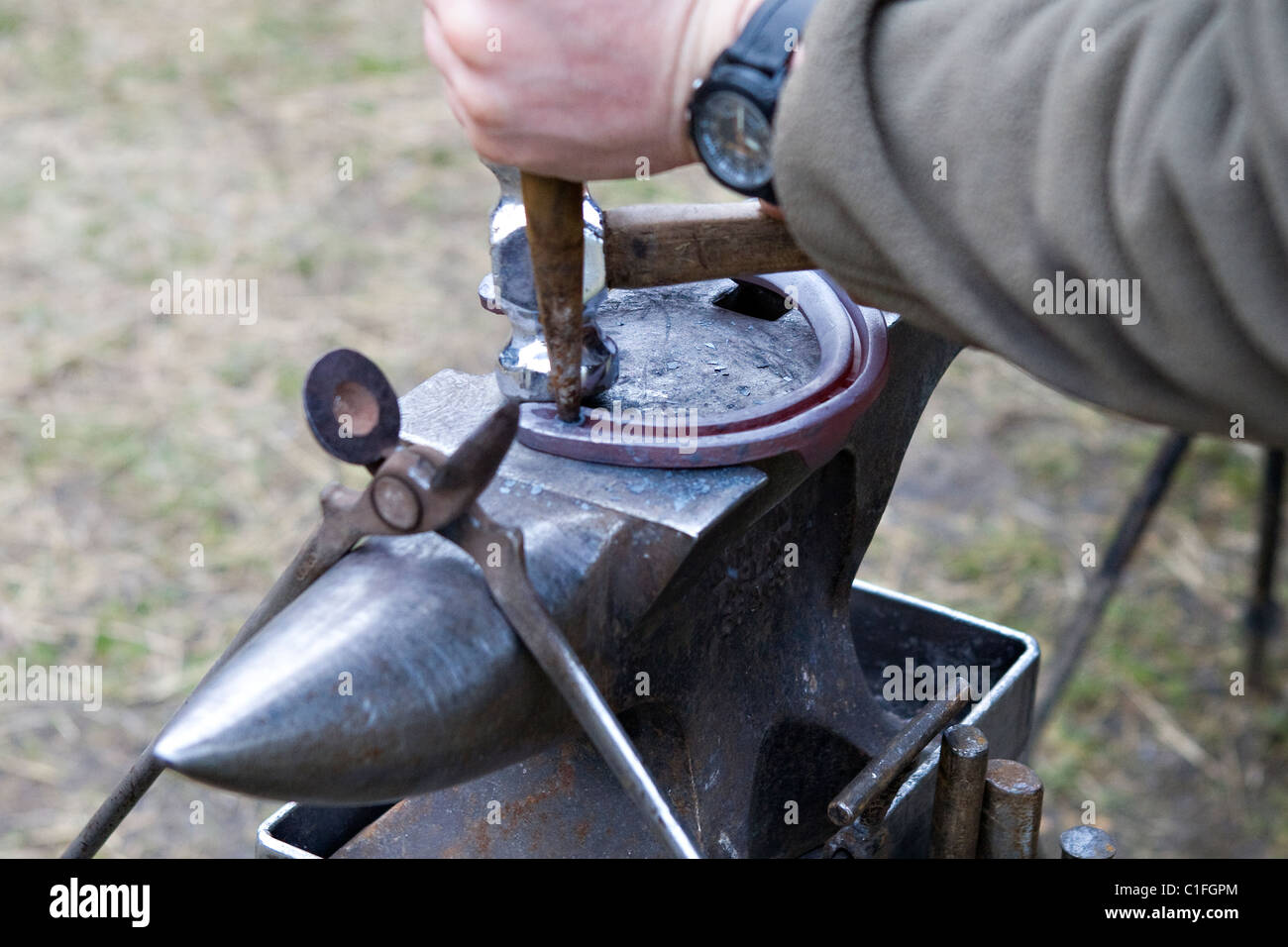 Farrier punching stud hole in horseshoe Stock Photo - Alamy