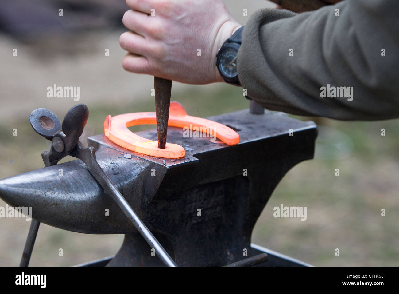Farrier punching stud hole in horseshoe Stock Photo - Alamy