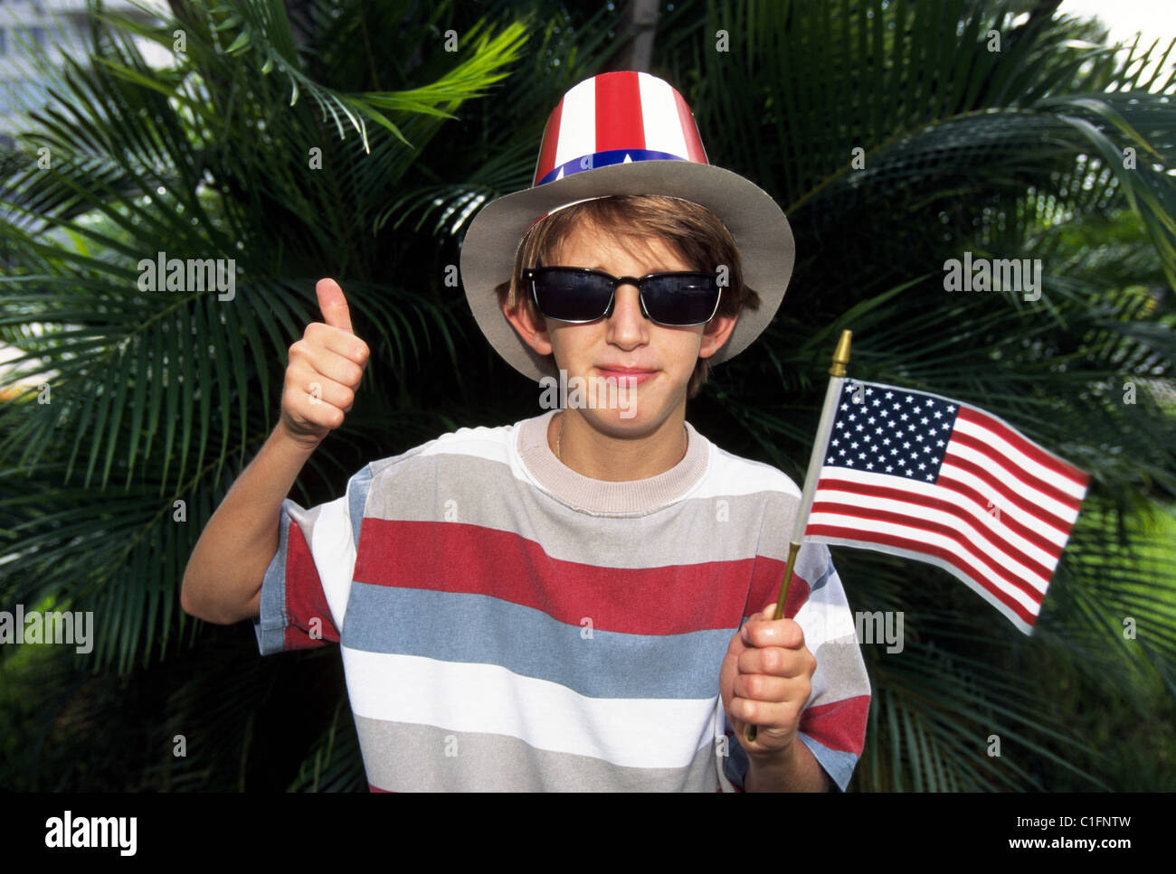 A patriotic boy in an Uncle Sam hat waves the American flag during an ...