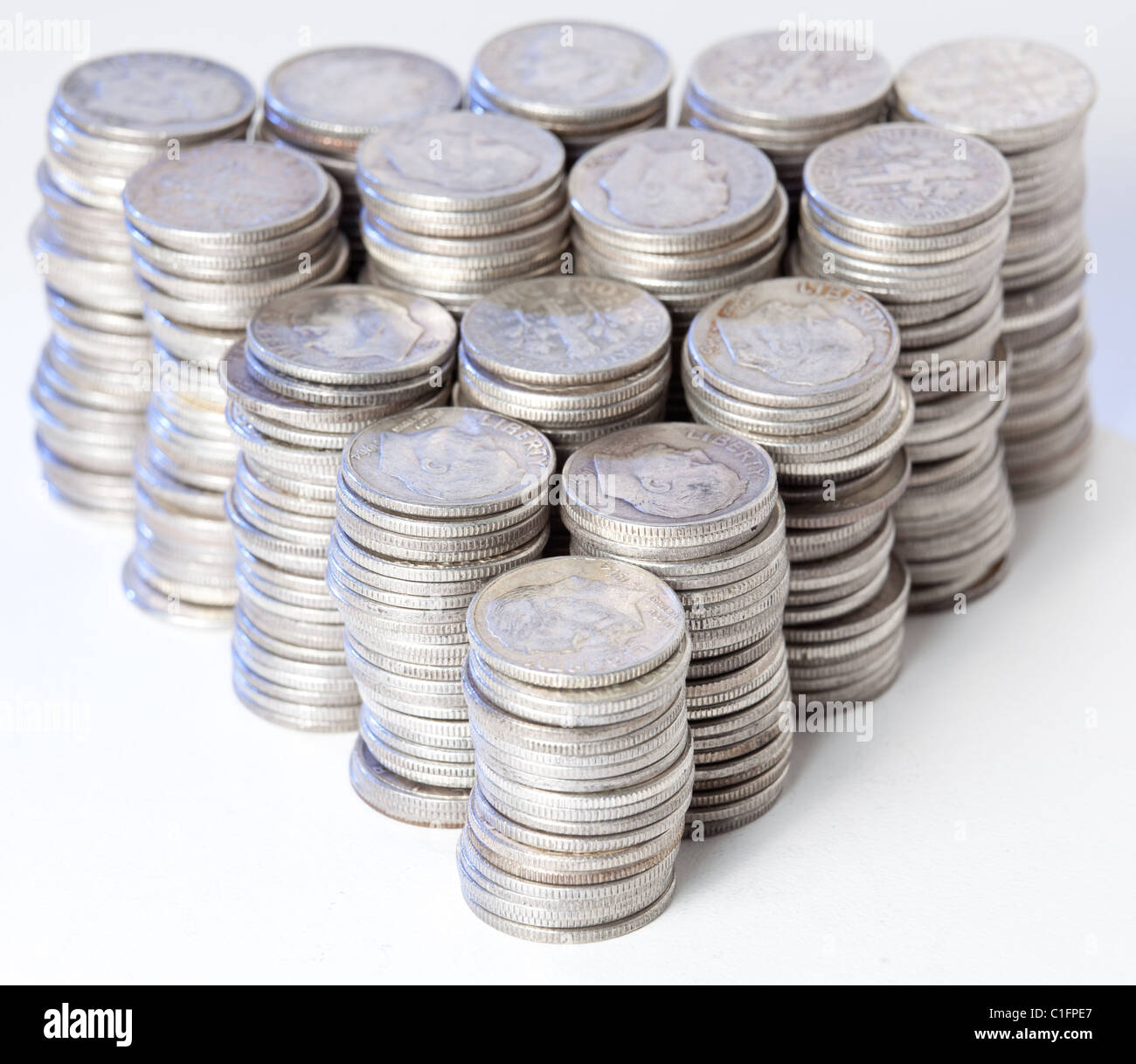 Many stacks of old silver dimes face on to camera and illuminated with ...