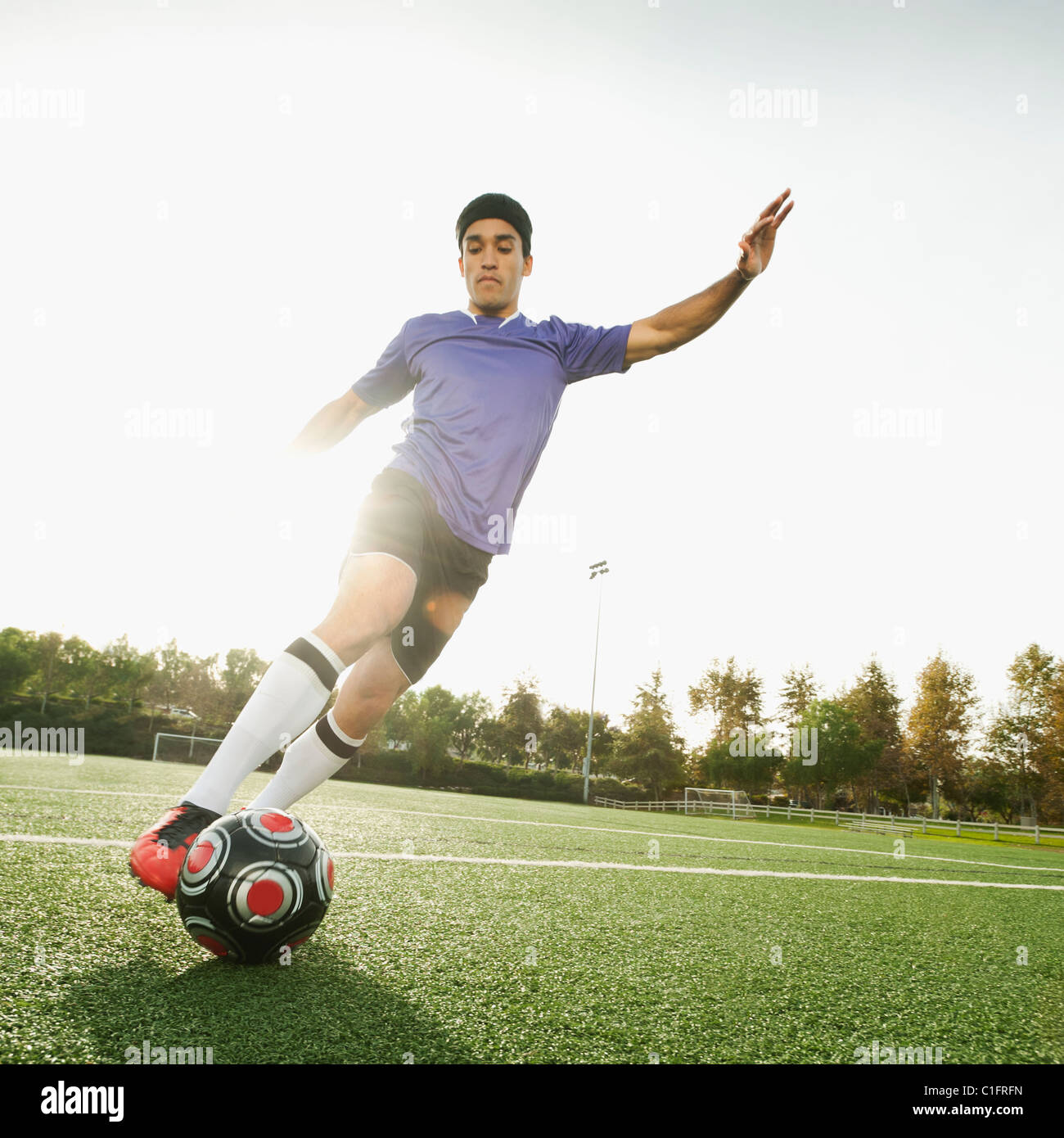 Mixed race soccer player kicking soccer ball Stock Photo - Alamy