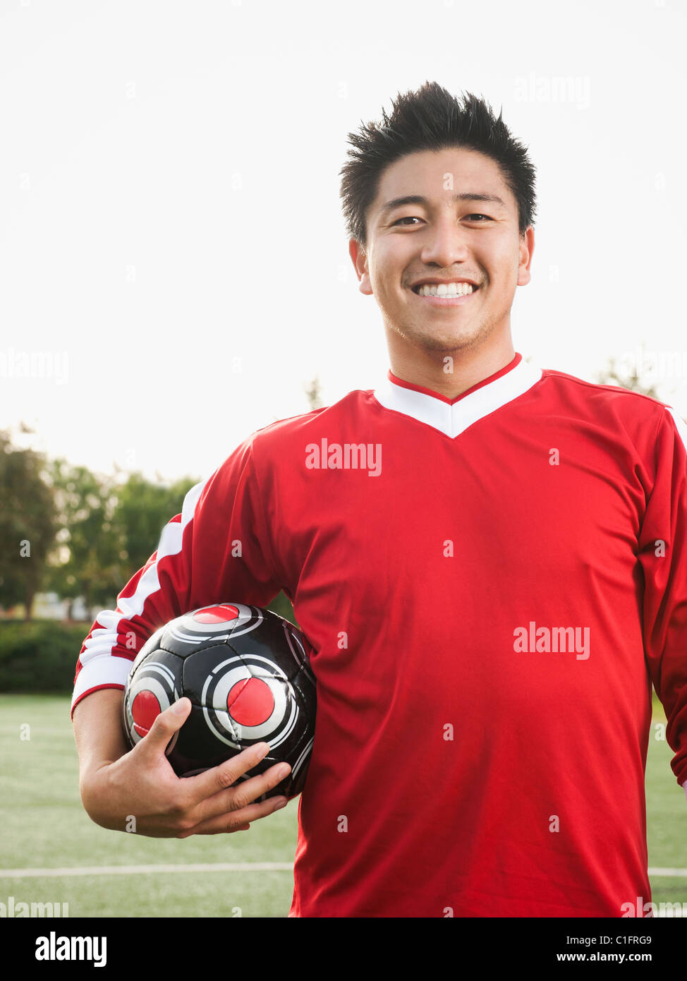 Asian soccer player holding ball on soccer field Stock Photo - Alamy