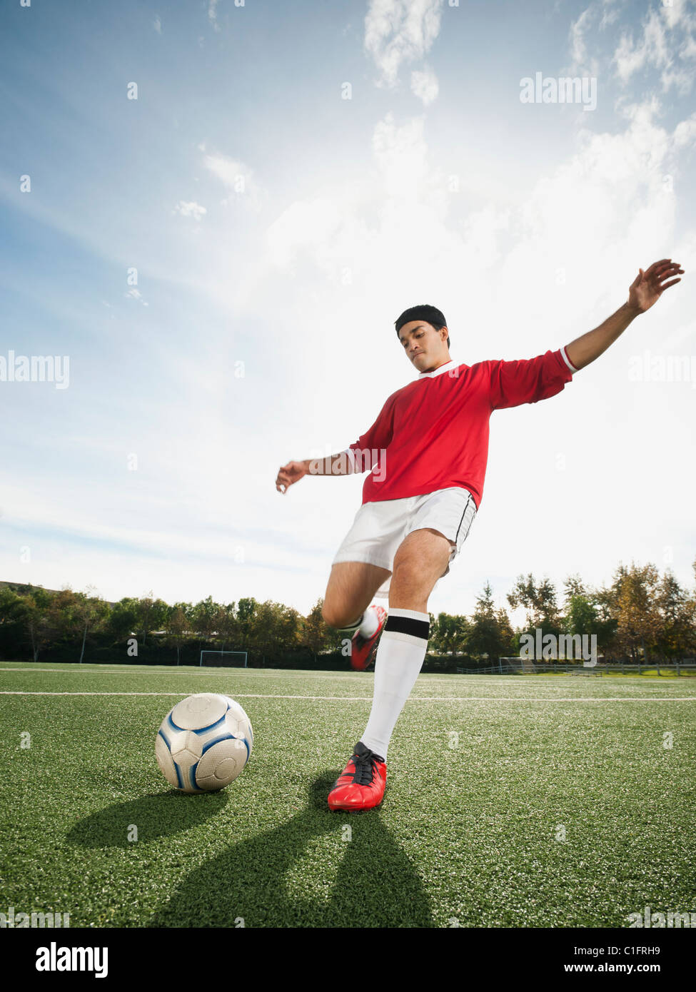 Mixed race soccer player kicking soccer ball Stock Photo - Alamy