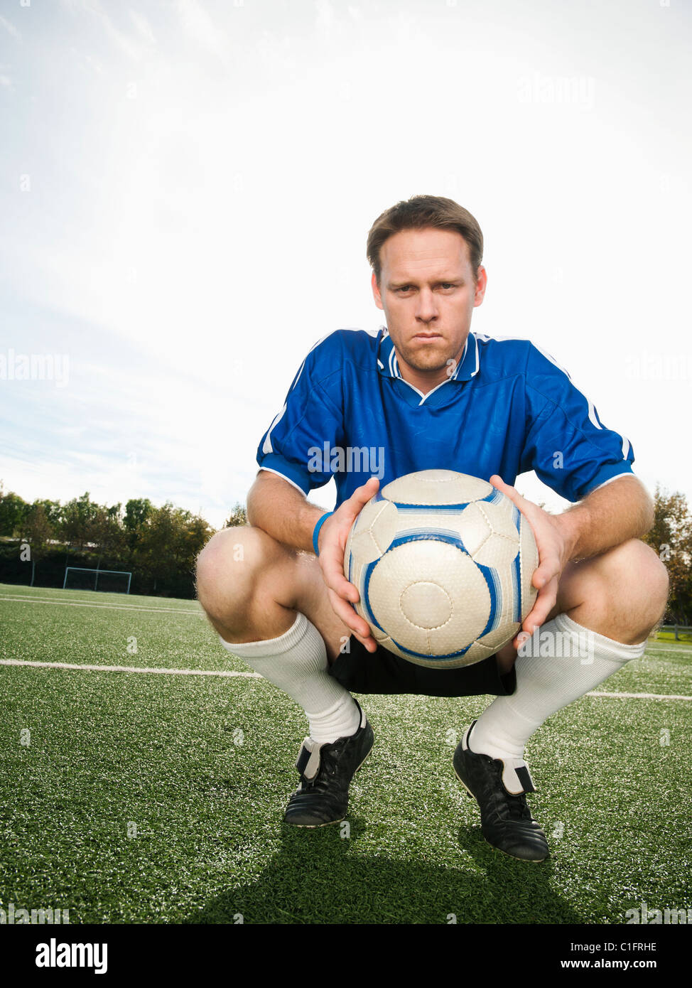 Caucasian soccer player crouching holding soccer ball Stock Photo - Alamy