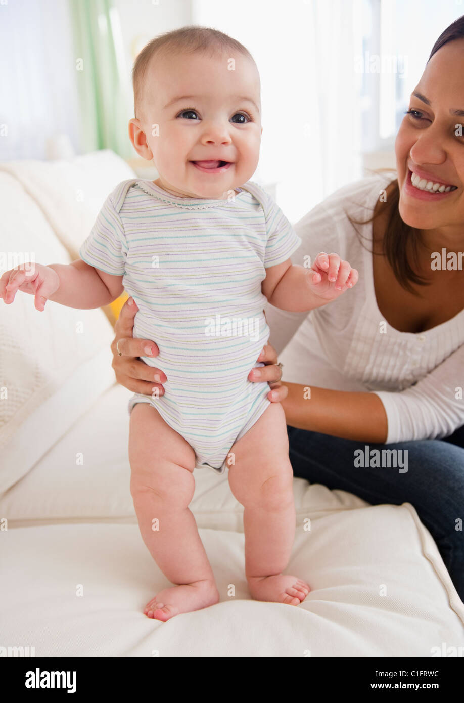 Mother supporting baby on sofa Stock Photo - Alamy