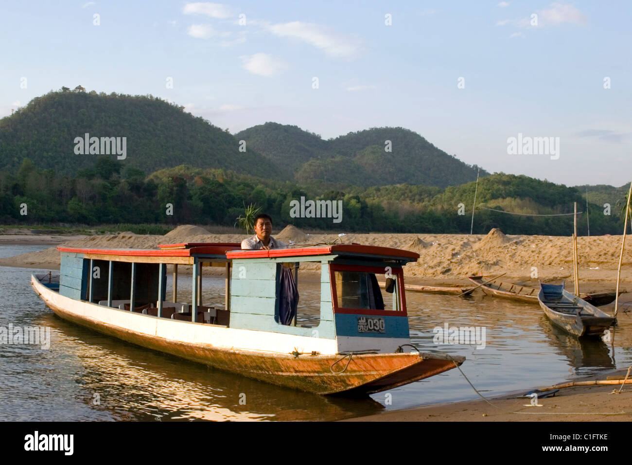 A colorful small wooden passenger ferry boat rests along the shore of ...